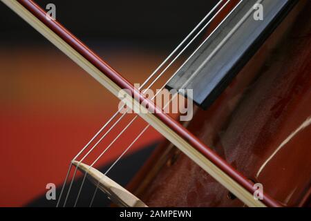 Close up of cello being played with hand and bow in shot with sunlight ...