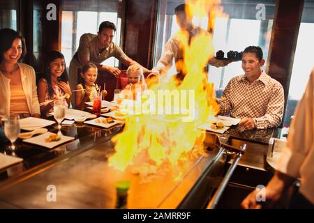 Family at a Japanese teppanyaki restaurant, watching the chef fire the ...