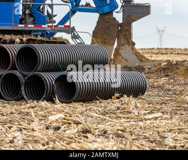 Field tile plow machine in farm field. Water drainage, soil ...