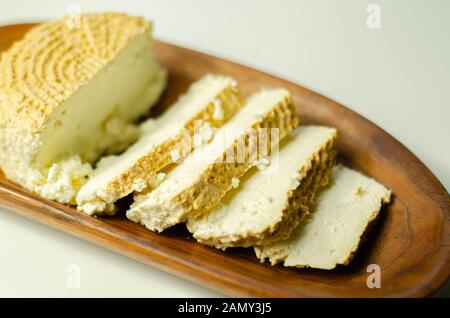 Smoked cottage cheese, brined cheese cut on a plate, a traditional and ...
