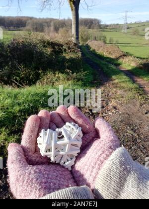 Gloved hands holding white heart Stock Photo - Alamy