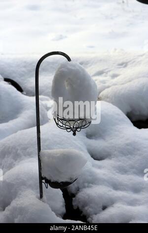 Snow piled high on a solar light and iris leaves after an early ...