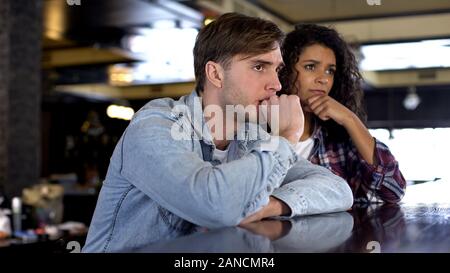 young multiethnic couple cheering while watching sport match in living ...