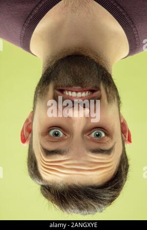 Smiling cute, looks happy. Inverted portrait of caucasian young man on ...