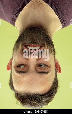Smiling cute, looks happy. Inverted portrait of caucasian young man on ...