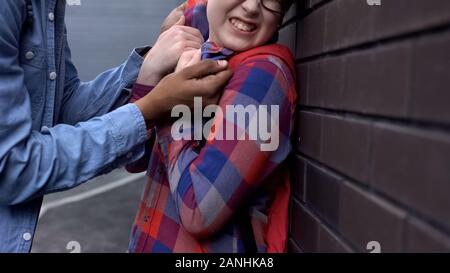 Cruel teenager pushing nerd boy to wall, threatening physical harm ...