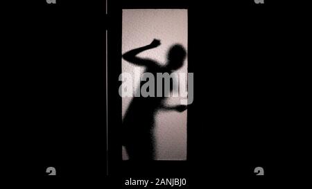Shadow of scared woman knocking at glass door, escape from captivity ...