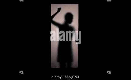 Shadow of scared woman knocking at glass door, escape from captivity ...