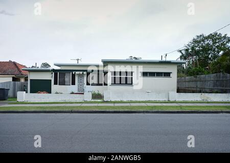 Skillion roof, mid-century modern house with a large, flowing Poinciana ...