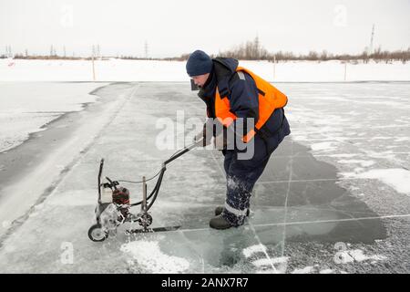 Worker cuts out ice blocks in size on the ice of a frozen lake Stock ...