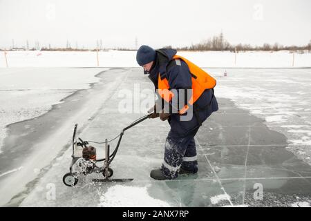 Worker cuts out ice blocks in size on the ice of a frozen lake Stock ...