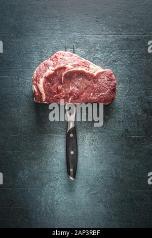 Rib eye raw fillet with fork and knife,salt and pepper with rosemary on ...