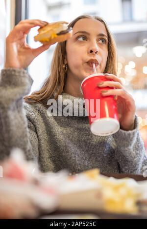 Attractive and beautiful girl enjoys her food in the lunch bar while ...