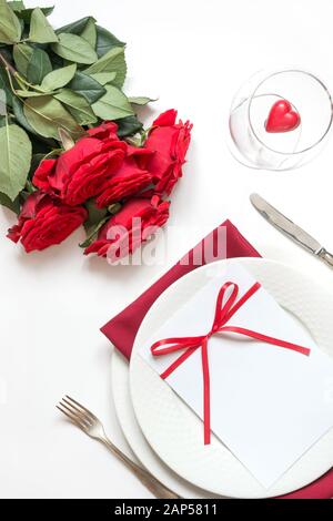 Romantic table setting with bouquet of red roses and gift. Top view ...