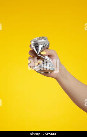 hand crushing a can of drink on red background Stock Photo - Alamy