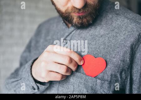 Young bearded man with paper heart for Valentine's Day on yellow ...