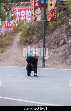 An old lady in excessive hunchback walking posture, life goes on ...