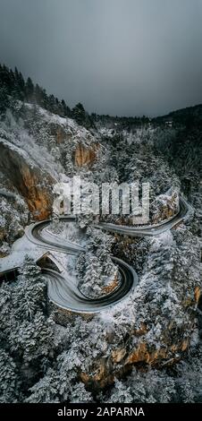 Curvy windy road in snow covered forest, top down aerial view Stock ...