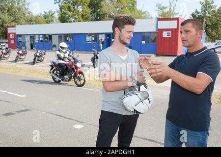 motorcycle driving instructor talking to candidate Stock Photo - Alamy