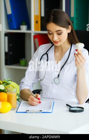 Beautiful blonde nutritionist woman holding fat pills skeptic and ...