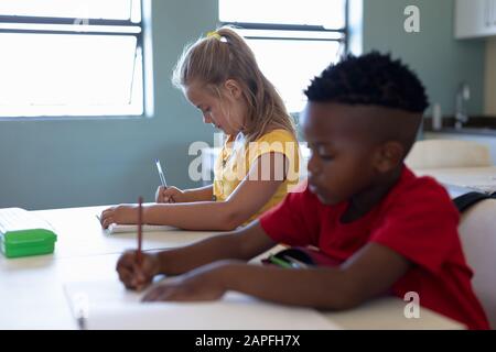 Elementary schoolchildren writing at the desk in the classroom Stock ...