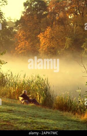 A man is fishing with his seat in the water on "Winter Begins" day of ...
