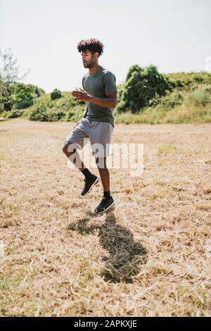 Young curly man jogging in the park spring afternoon Stock Photo - Alamy