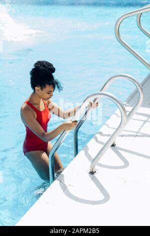 Young woman entering swimming pool Stock Photo - Alamy