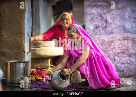 Young Indian woman washing dishes outside their rural indian village ...