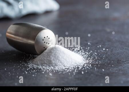 Spilled white sea salt on a black background. clear crystalline pebbles ...