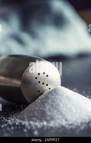 Salt shaker and pile of spilled Sea salted on a black kitchen table ...