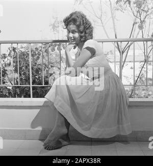 Portrait of Nurit Makover seated on the concrete edge of a balcony ...