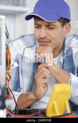 Confused computer engineer looking at wires Stock Photo - Alamy