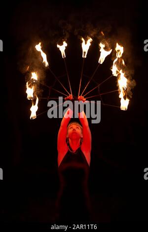 female fire performer holding lit fire fans Stock Photo - Alamy