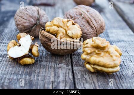 Peeled walnuts and walnut kernels lie on a rustic old wooden table ...