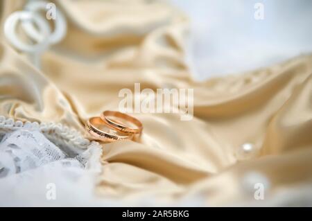 wedding rings with inscriptions in Latin lie on a two-color silk fabric ...