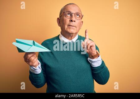 Senior handsome man holding airplane of paper standing over isolated ...