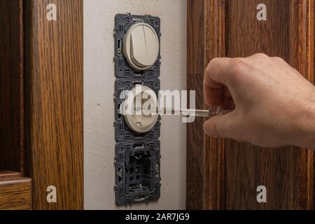 A master electrician mounts an electrical plug on a wall. Vintage ...