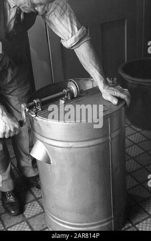 1950s, historical, making mead, a gentleman using a wooden mixing tool ...
