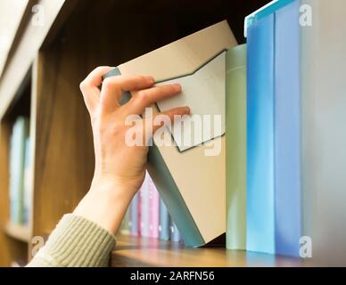 Hand pulling a book off the shelf Stock Photo - Alamy