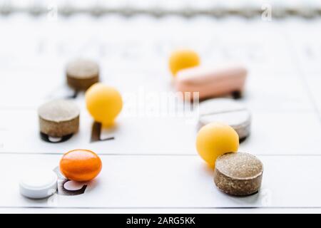 A bunch of different pills on a calendar background. Pills, supplements ...