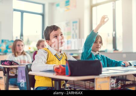 Boy student in class knowing an answer raising his hand Stock Photo - Alamy