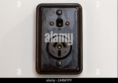 Old fashioned bakelite power socket with on/off switch on a white ...
