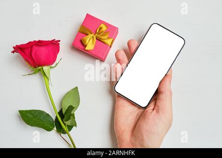 Red gift box next to gold tree toy ball and scissors on white wooden ...
