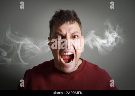 Aggressive man with steam coming out of his ears on orange background ...