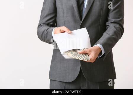 Businessman with bribe against light background Stock Photo - Alamy