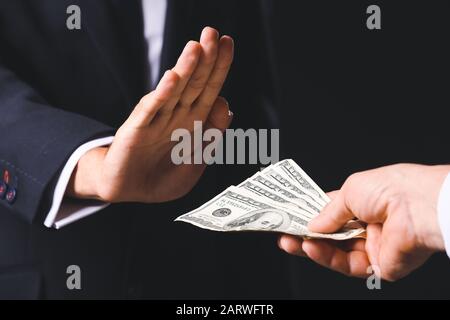 Businessman refusing to take bribe against dark background Stock Photo ...