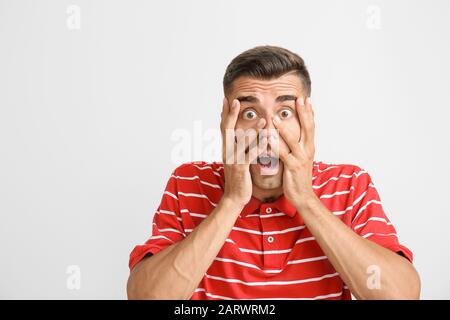 Shocked young man on light background Stock Photo - Alamy