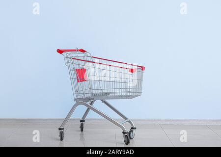 Empty shopping cart near color wall Stock Photo - Alamy