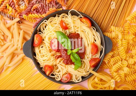 Composition with prepared spaghetti in pan, grater, cheese, wine bottle ...